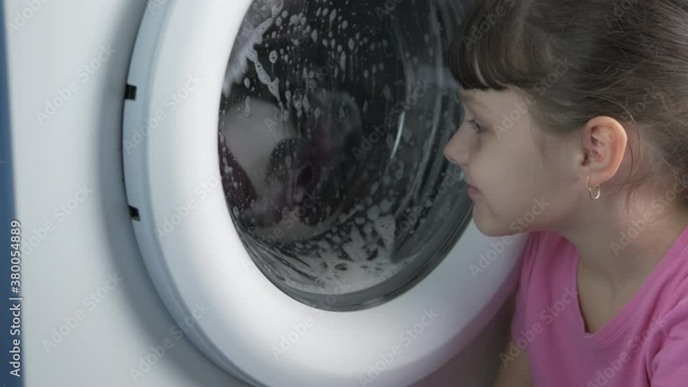A child at the washing machine. Little girl looks at toys in the ...