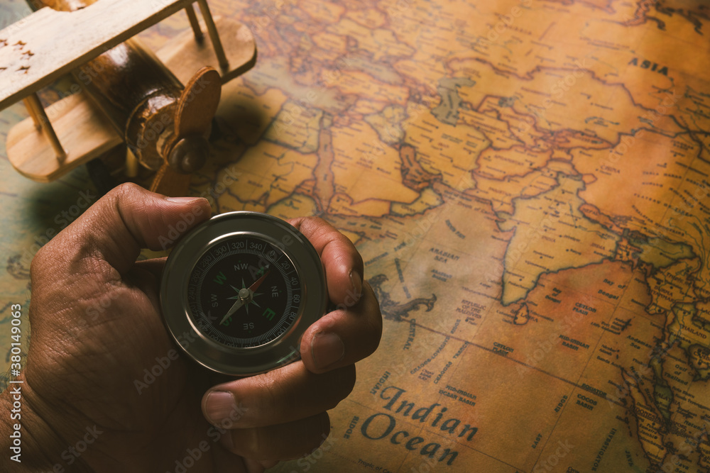 Hand hold old compass discovery and wooden plane on vintage paper ...