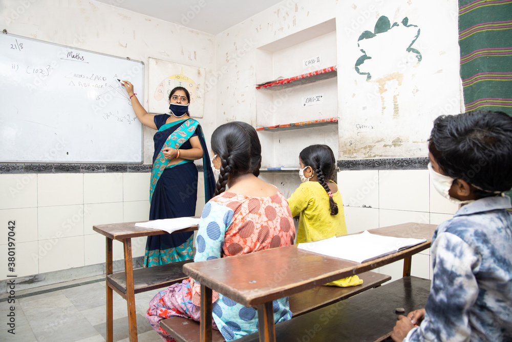 Indian teacher and students wearing face masks maintaining social ...