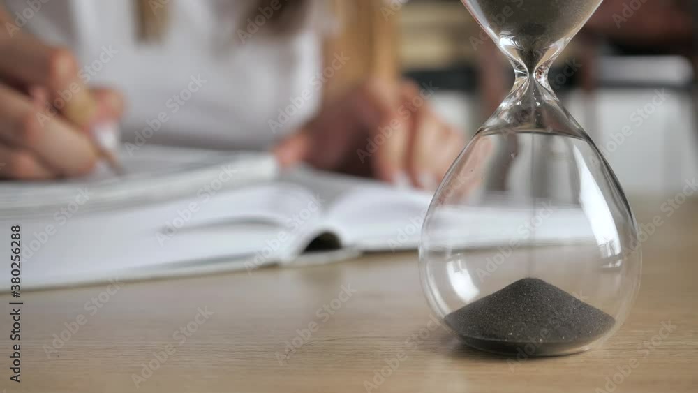 Hourglass black sand in a transparent flask is poured silhouette of a ...