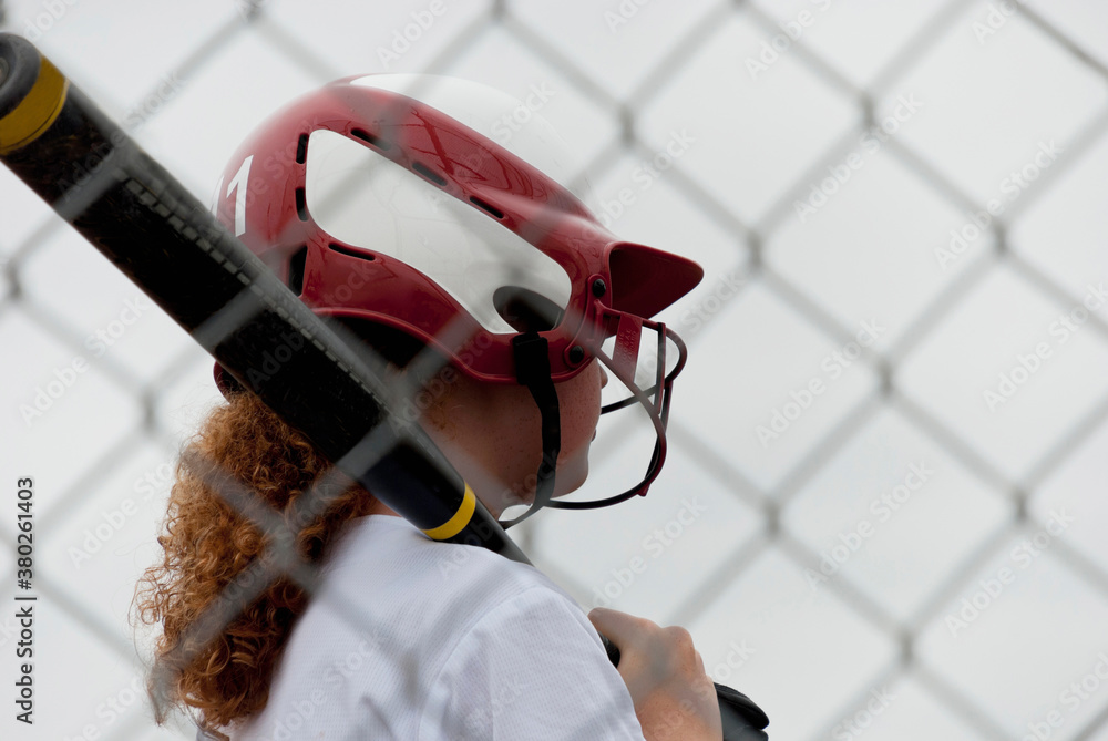 tween girl carrying her bat behind wire chain link fence Stock Photo ...