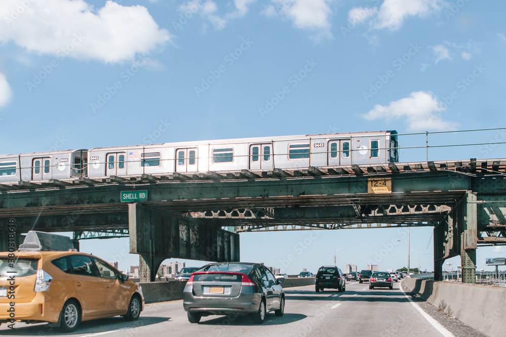 Horizontal photo of a subway train on an overpass over highway with ...