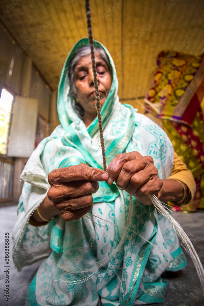 An old age woman is making on some fiber rope using on the banana tree ...
