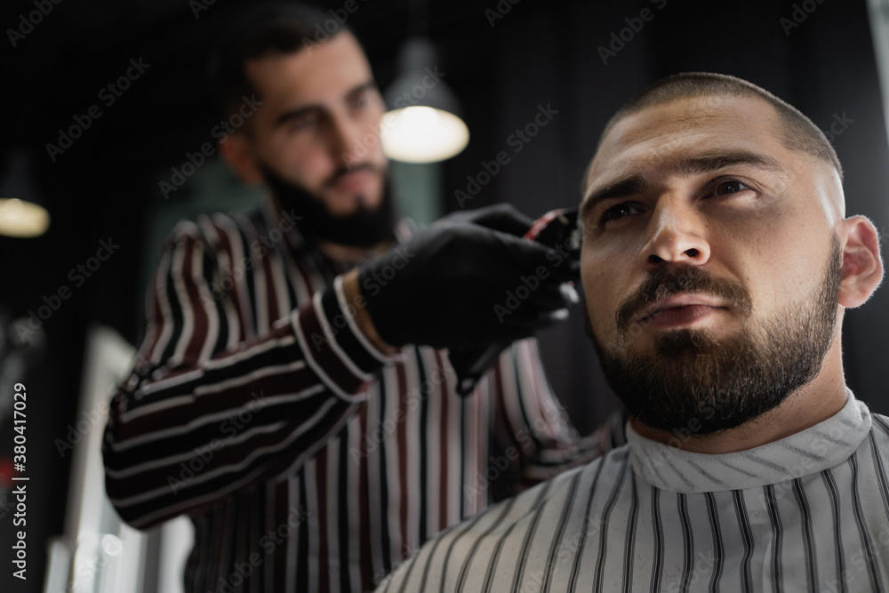 The master Barber of Caucasian appearance does his job, cuts the client ...