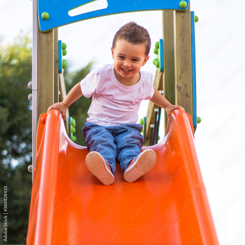 Foto de Child sliding down a slide in a playground do Stock | Adobe Stock