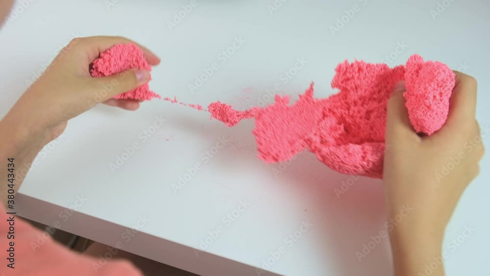A boy playing with slime, crushing squizing and crumpling pink ...