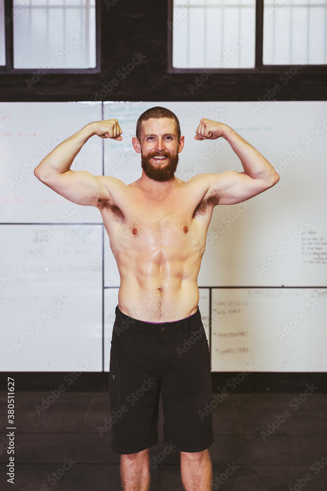 Portrait of an athletic man showing his biceps in a gym. Stock Photo ...