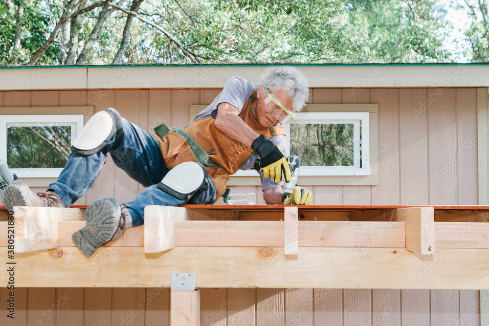 Elderly woman carpenter drilling a hole to build a wood shed Stock ...