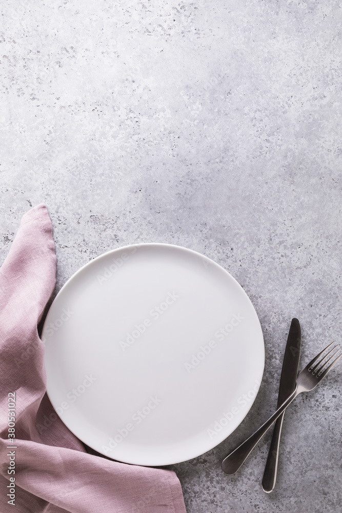 Ceramic plate, napkin and cutlery on the table with concrete texture ...