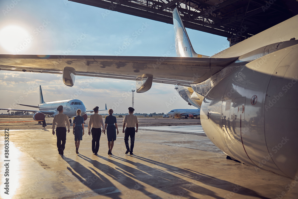 View of flight staff in the airport isolated on the sun and aircraft ...