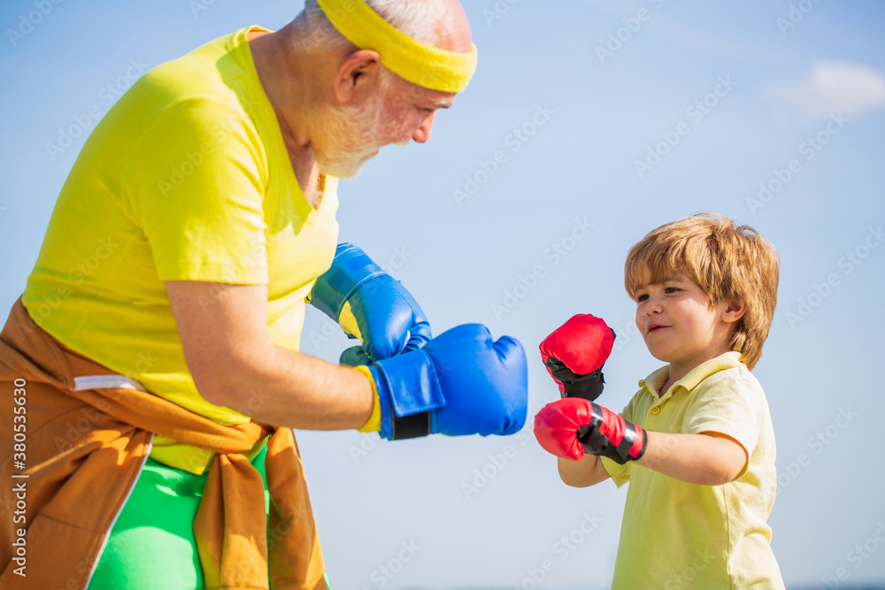 Little boy doing boxing exercise with grandfather. Father is training ...
