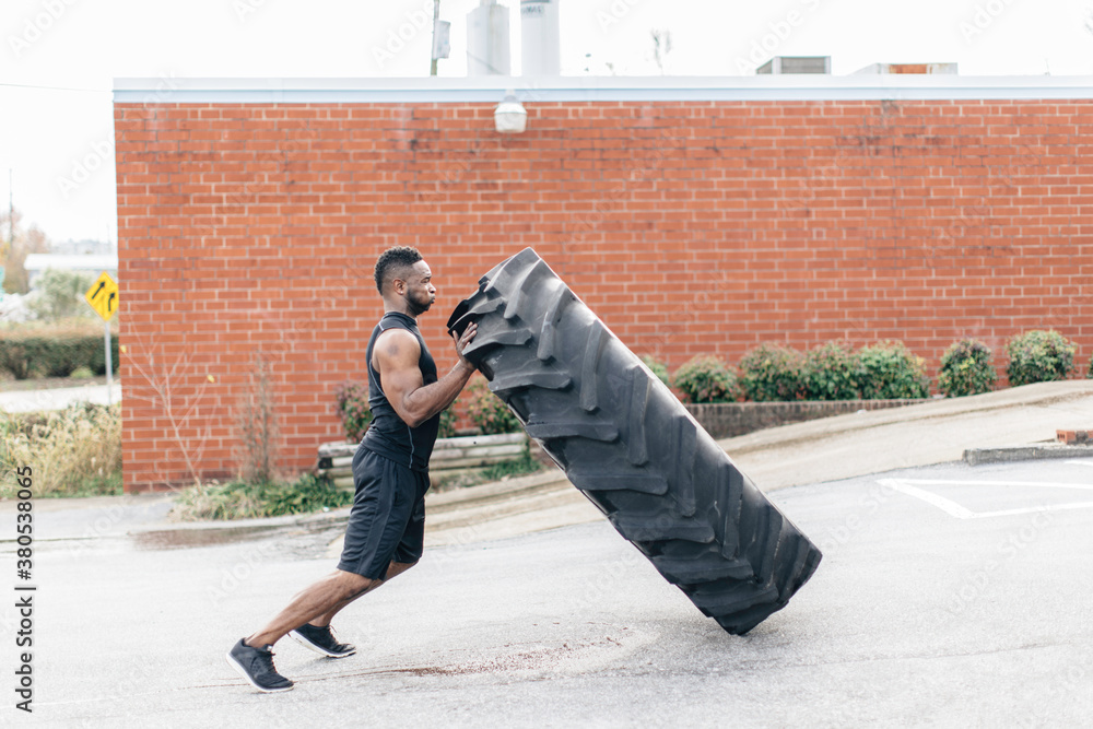 Strong and fit african american athlete flipping a tractor tire Stock ...