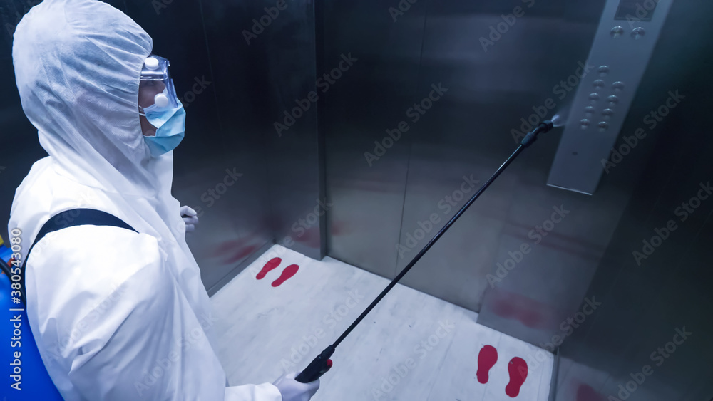 Worker in personal protective equipment (ppe) suit cleaning in building ...