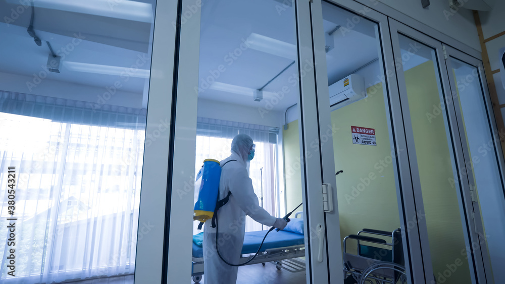Worker in personal protective equipment (ppe) suit cleaning in building ...