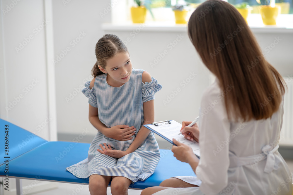 Girl having a stomach ache and talking to the female doctor Stock Photo ...