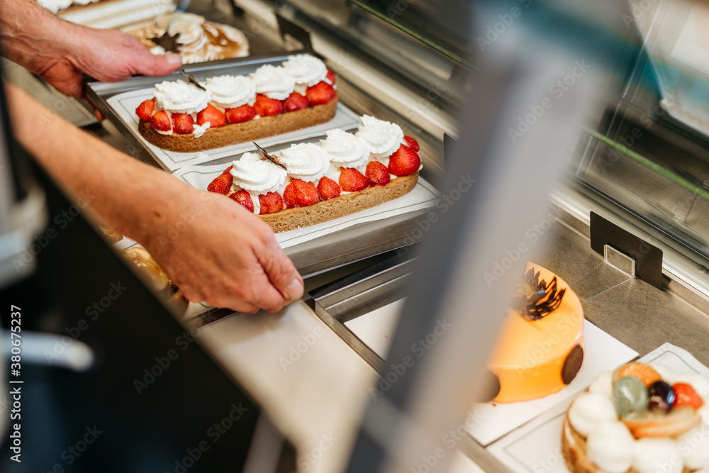Baker putting delicious pastry on the store showcase of the bakery ...