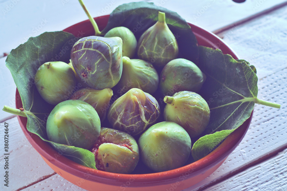 Higos verdes sobre sus hojas en un bol de barro, frutas de temporada ...