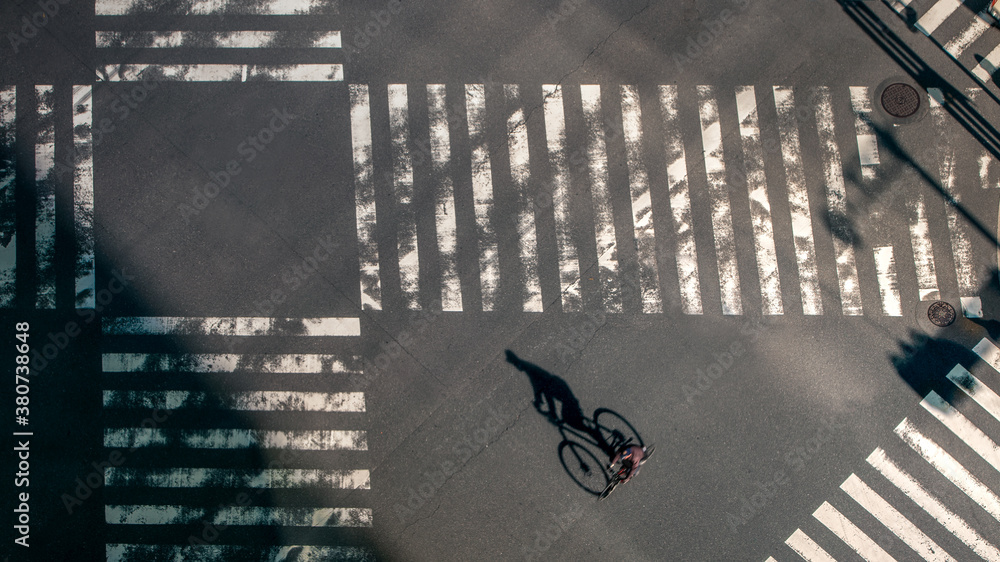Elevated view over a biker man on pedestrian crossing in road ...