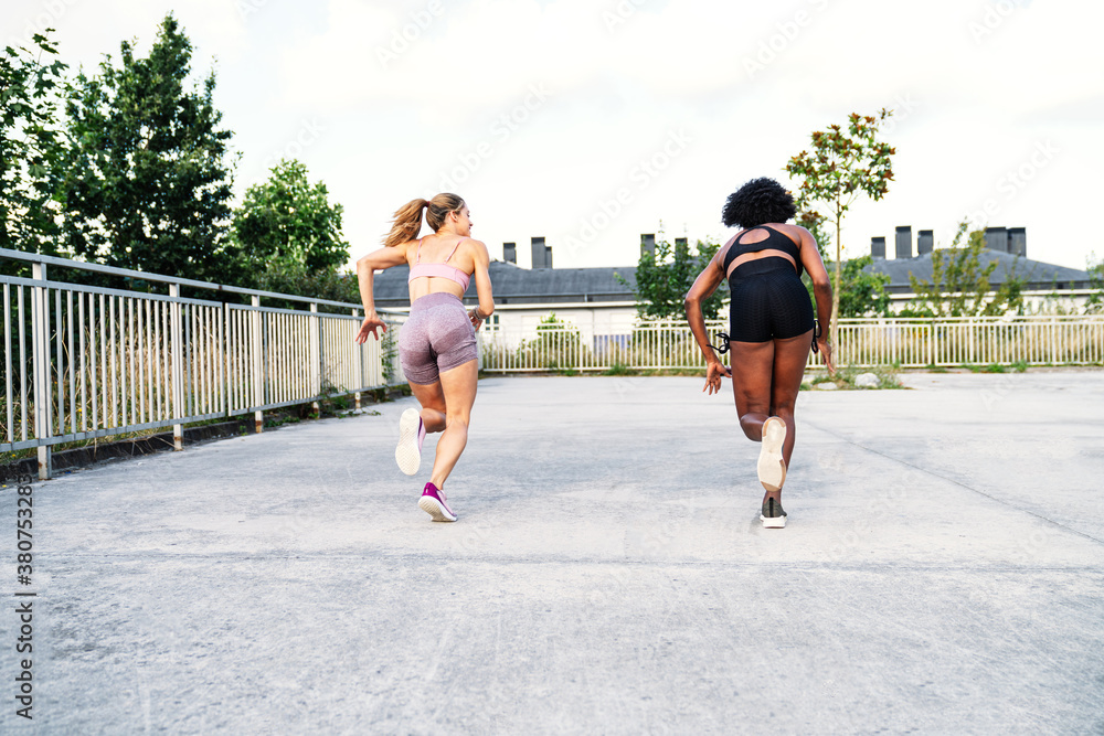 Foto de Sportive multiethnic females in activewear competing with each ...