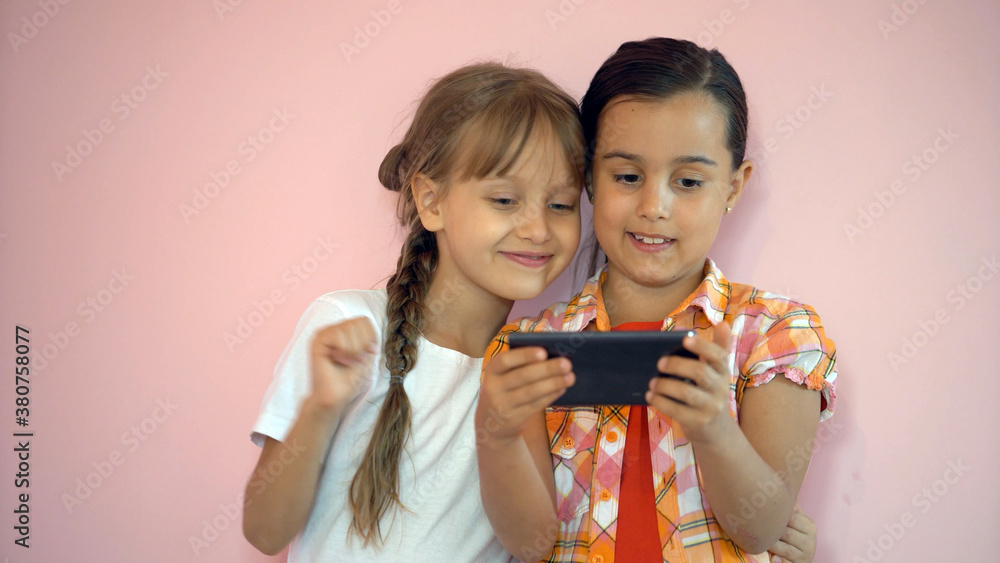 Happy little girls with a smartphone in hands communicate at home with ...