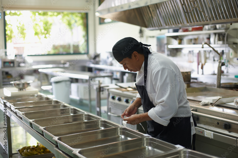 Cook preparing many food trays in the kitchen Stock Photo | Adobe Stock
