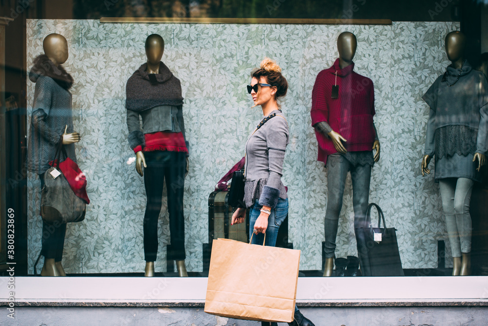 Woman walking next to window of a clothing store with a bag Stock Photo ...