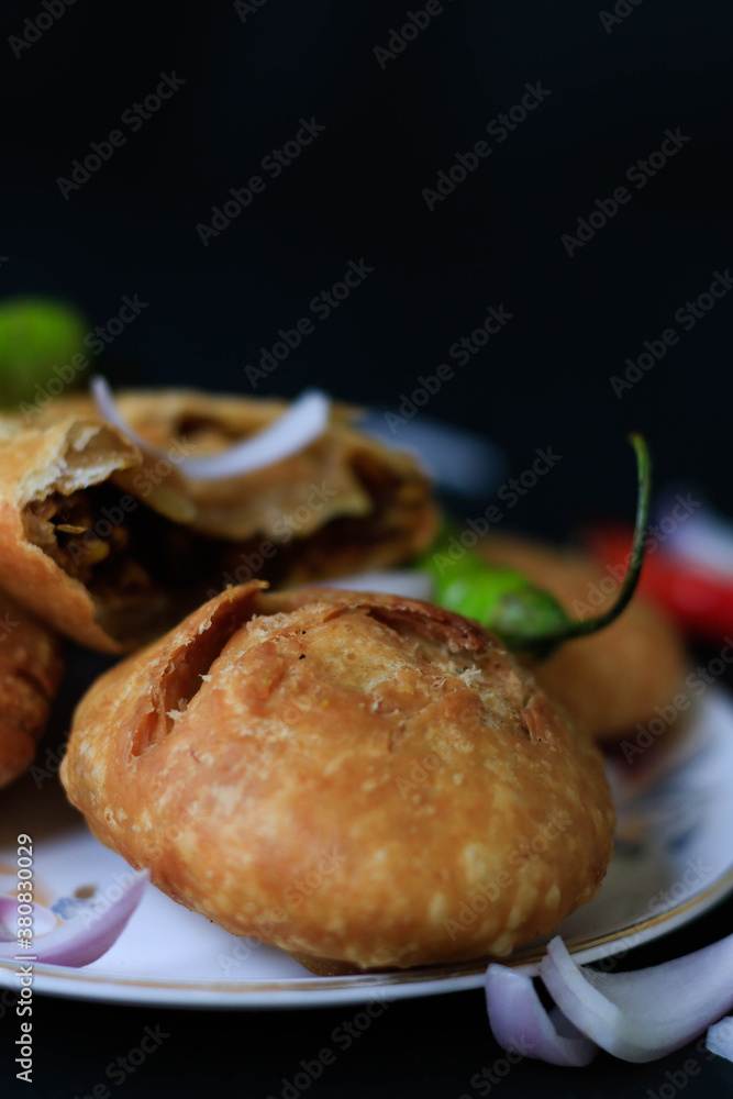 Indian snack kachori served with green chilli and onions in a black ...