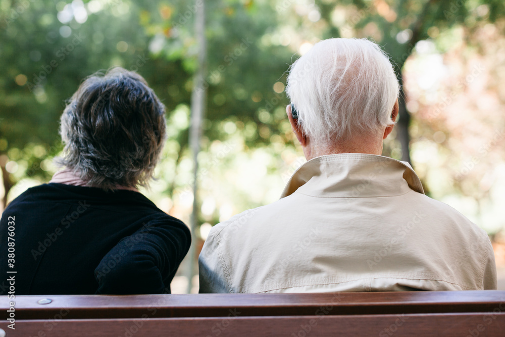 Back view of an elderly father and his daughter sitting on bench. Stock ...