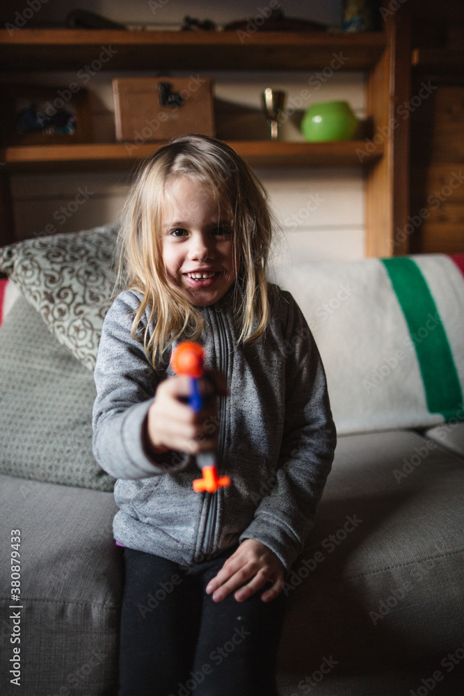 Little girl smiing and pointing toy gun Stock Photo | Adobe Stock