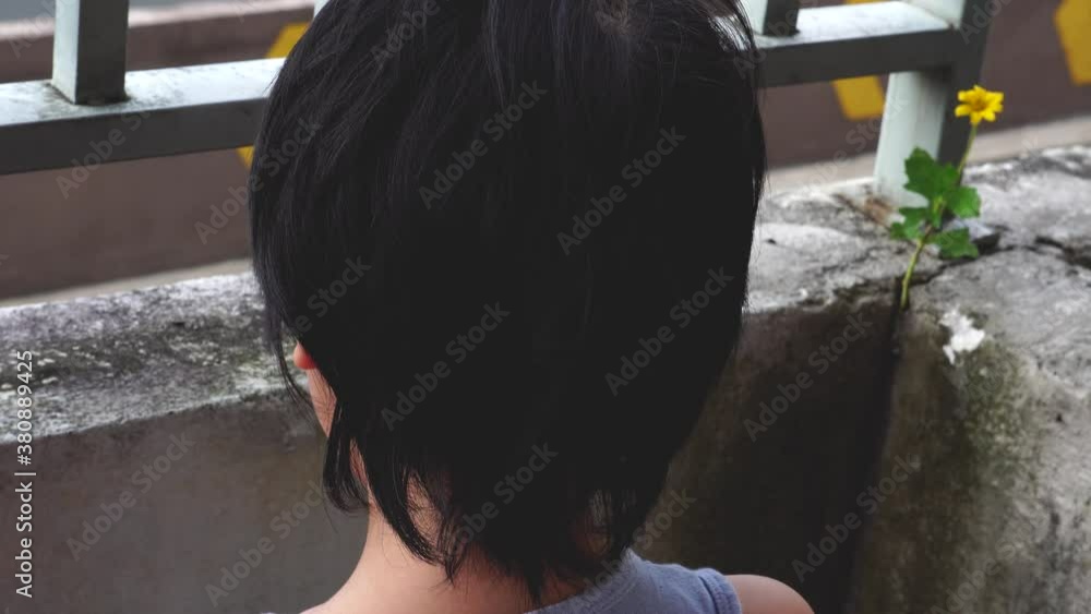 Boy outdoors alone peering over ledge while among the grunge and grime ...
