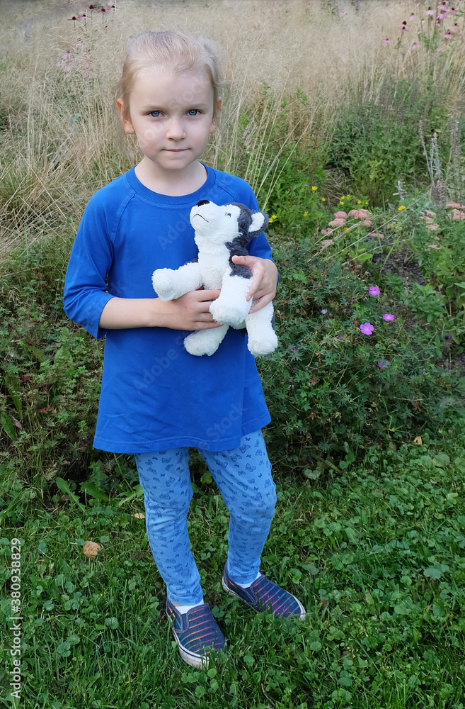 A little girl with blond long hair tied up in a ponytail in a blue ...