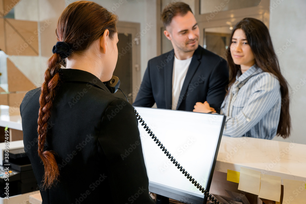 Couple and receptionist at counter in hotel. Young couple checking in ...