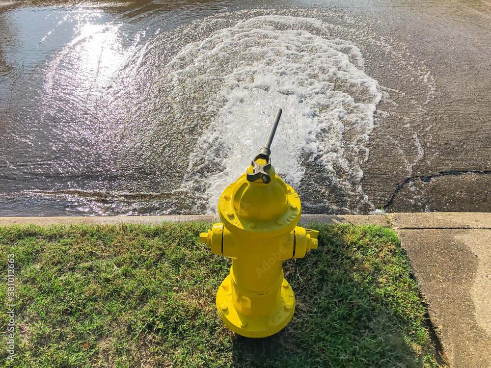 Top view yellow fire hydrant gushing water across a residential street ...