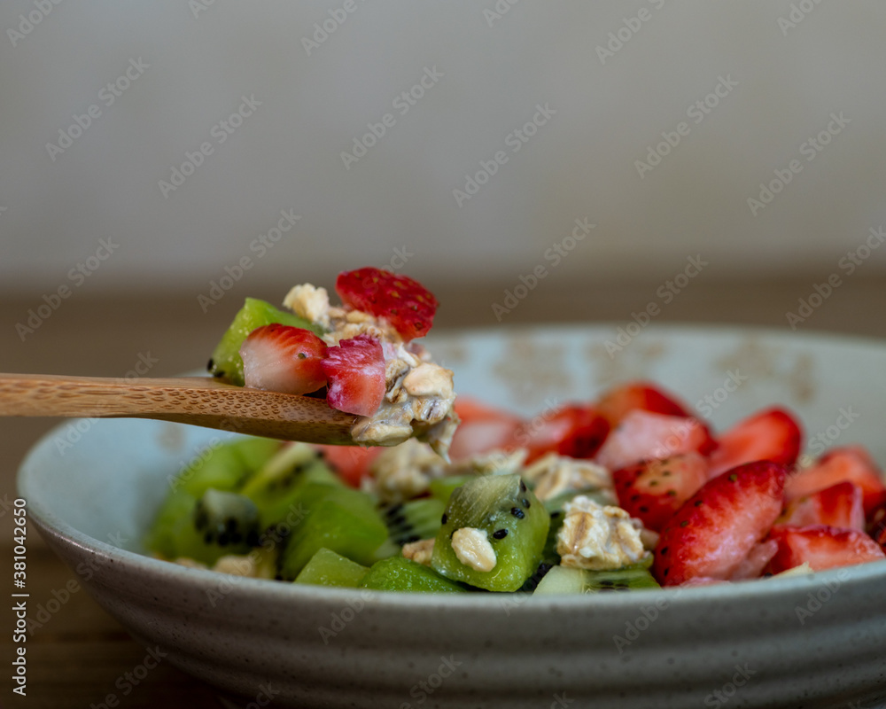 Wooden spoon picking up a serving of oatmeal from a tan plate garnished ...