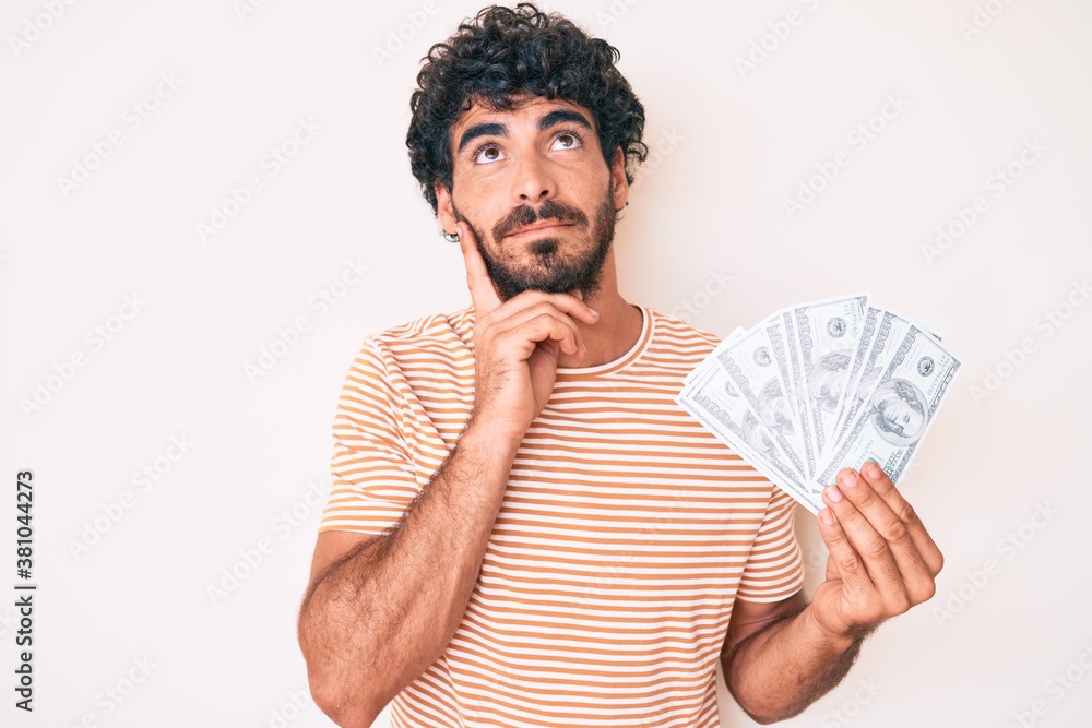 Handsome young man with curly hair and bear holding money bag with ...