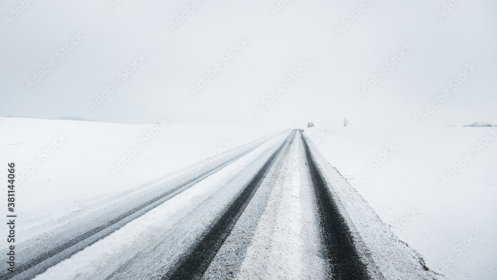 Snow-covered highway (asphalt road) through the country fields in a fog ...