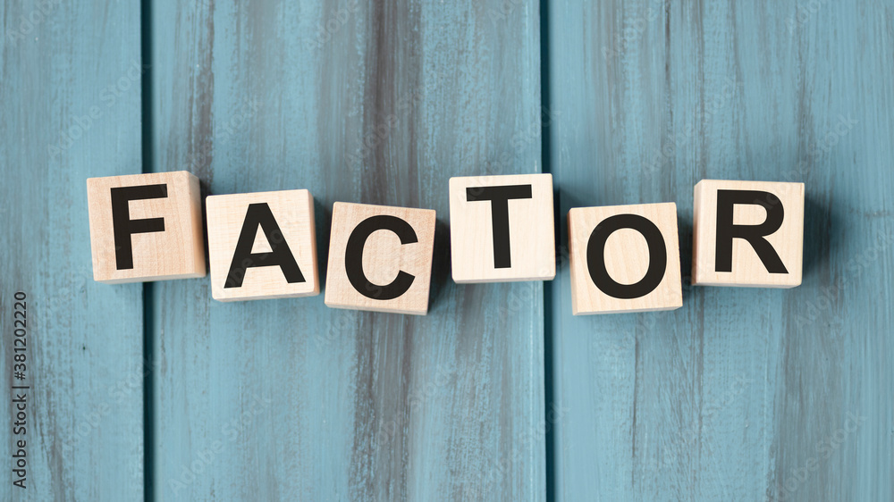 word factor made from wooden gray letters lies on a green background ...