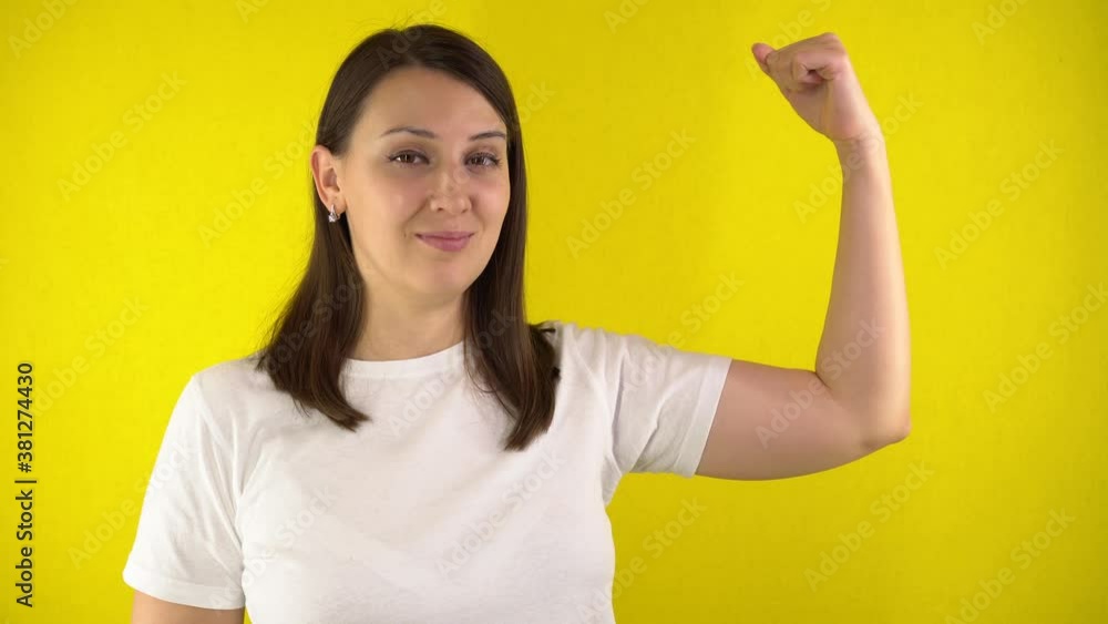 A young woman shows strength in her hand. A woman in a white T-shirt ...