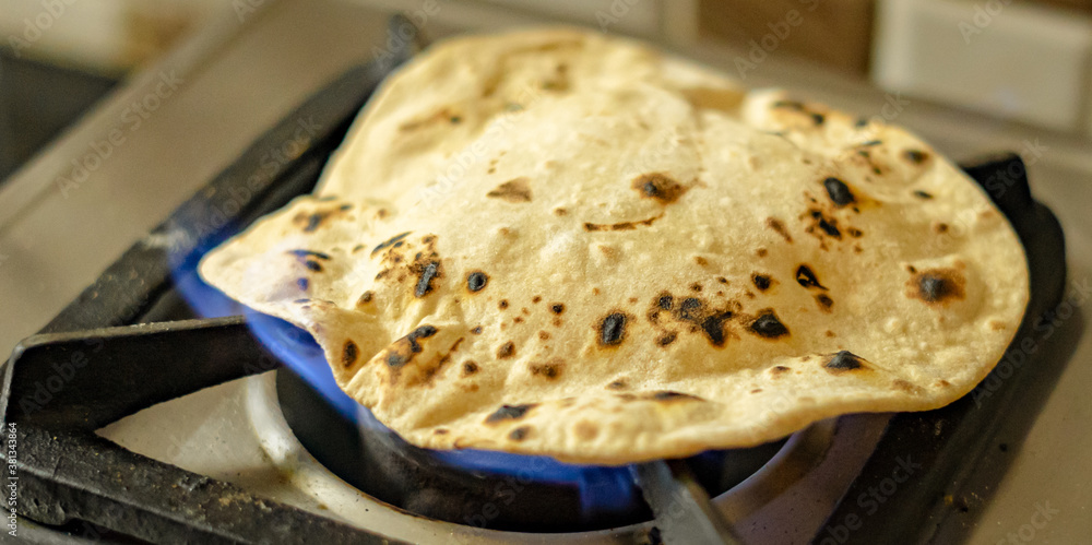 Wheat chapati or roti cooked on fire using a gas stove Stock Photo ...