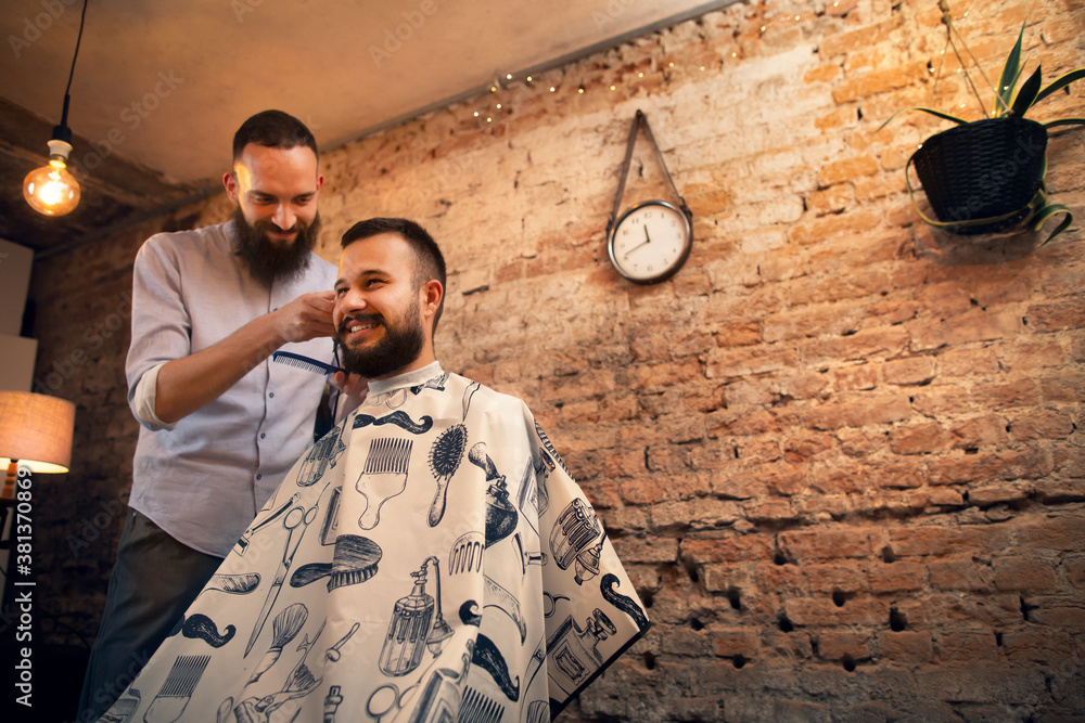 Good looking man visiting barber shop. The barber cuts his hair and ...