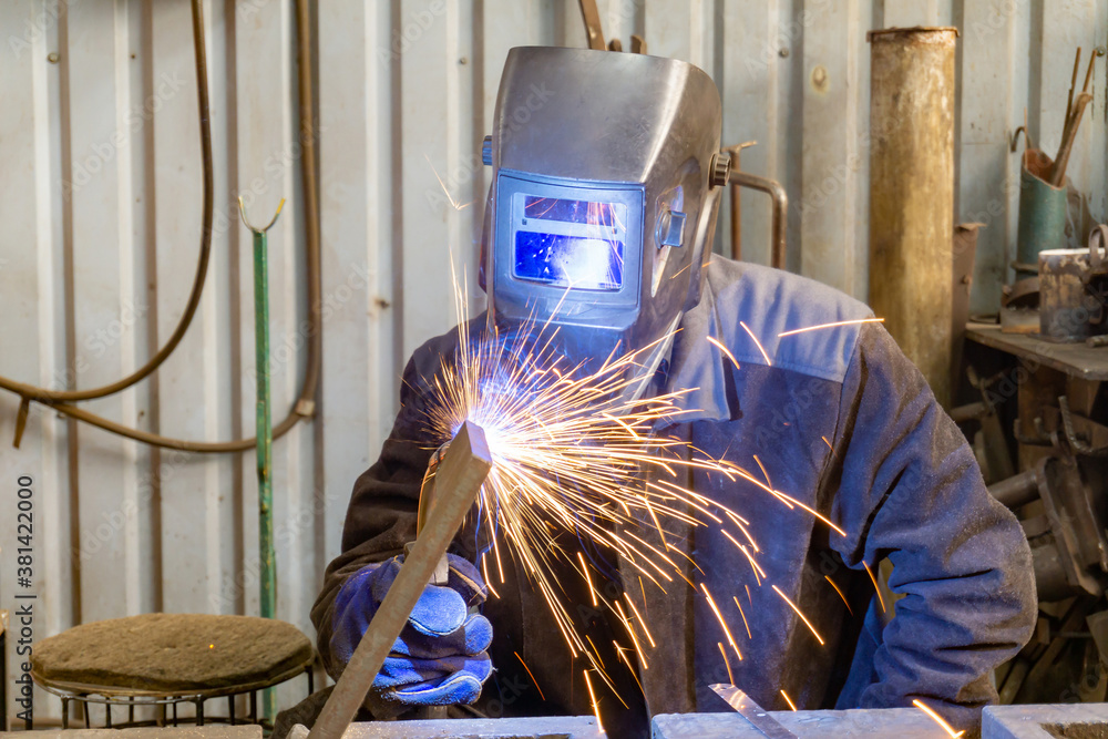 An electric and gas welder in an electromechanical workshop welds a ...