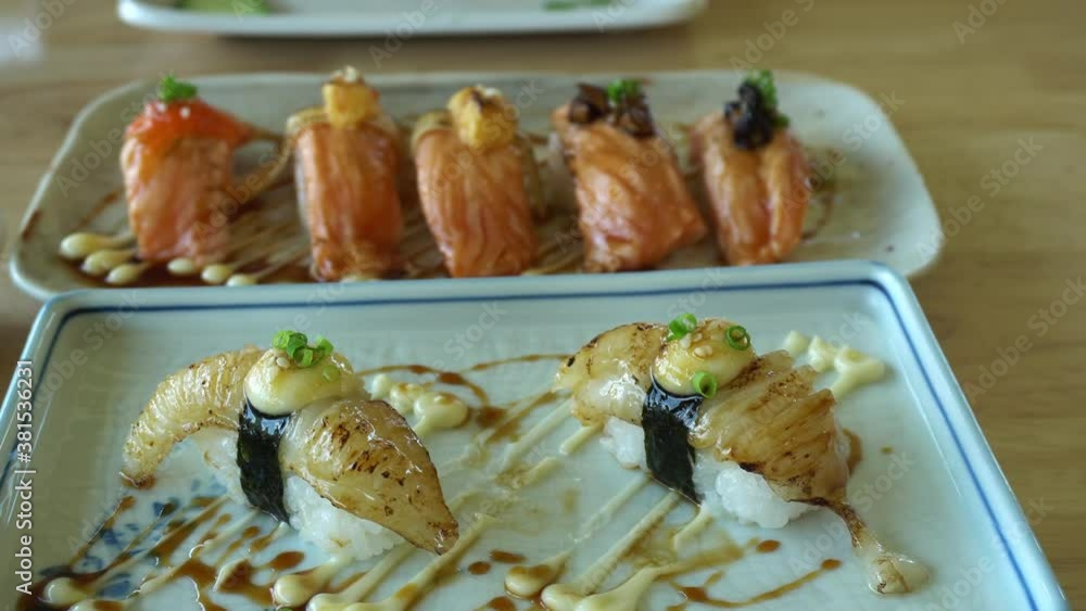 hands eating aburi engawa nigiri or flounder fin burnt sushi with sauce ...