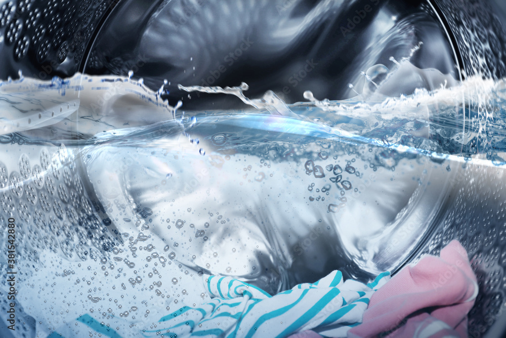 Washing machine drum with water and clothes, closeup view Stock Photo ...