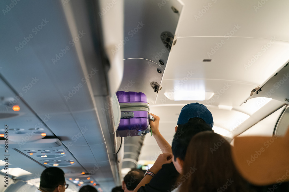 Hand take off hand luggage. Bag cabin on top shelf in airplane Stock ...
