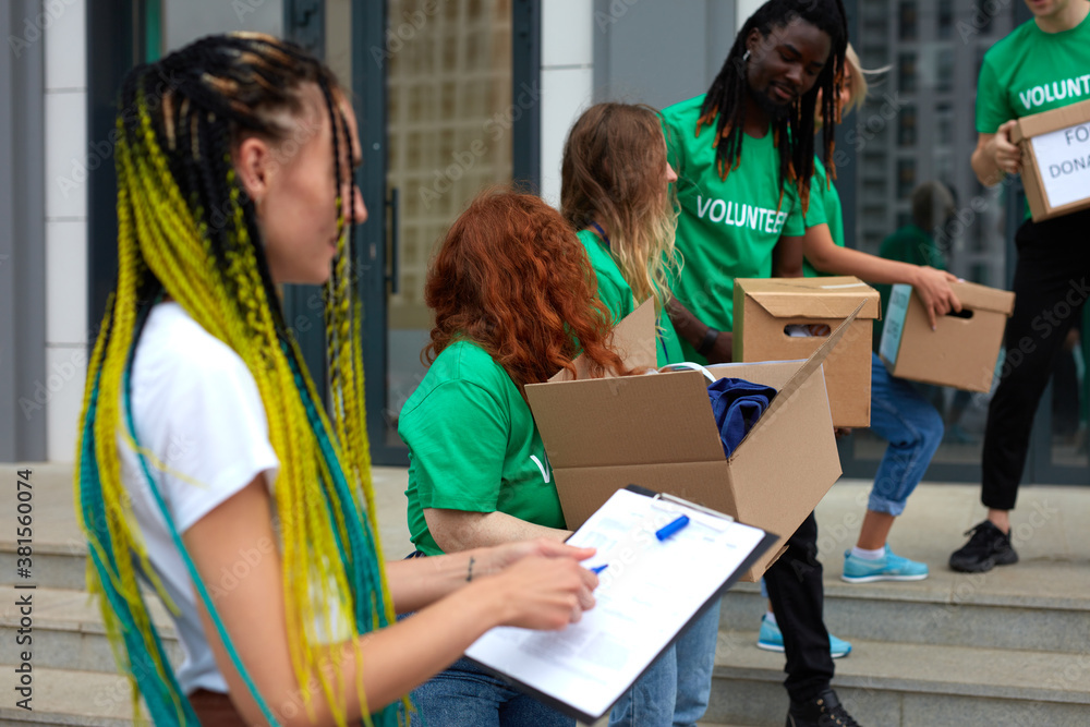 diverse volunteers packing, collecting humanitarian aid in donation box ...