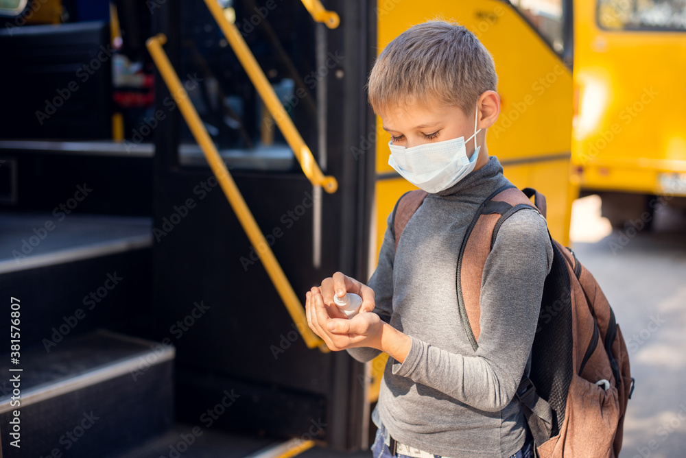 Elementary school learner sanitizing hands before going into the school ...