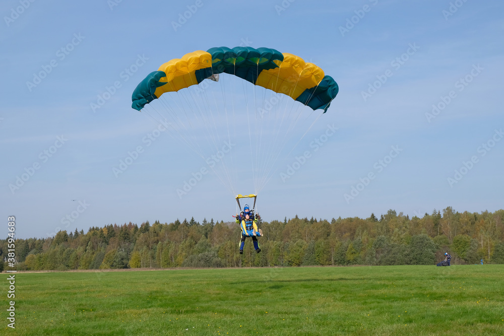Tandem skydiving. A tandem is landing on the green field. Stock Photo ...