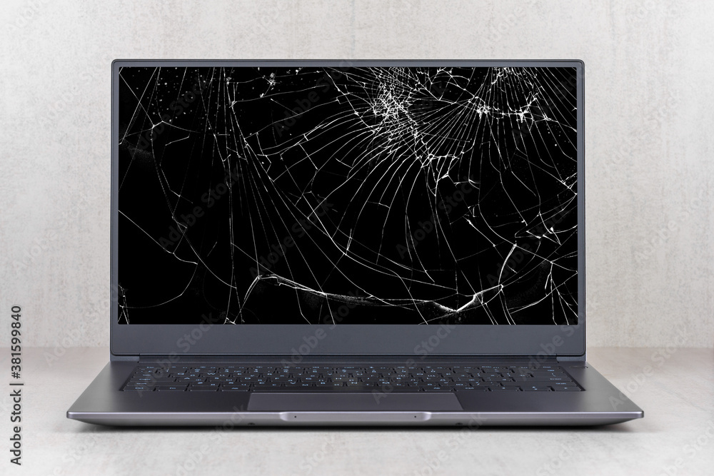 laptop with a broken screen in cracks on a gray background close up ...