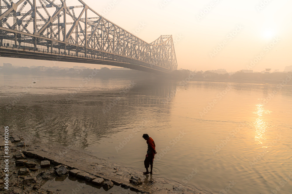 Howrah Bridge at the time of Sunrise. People bathing in the River ...