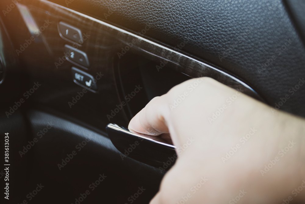 The driver's hand unlocks the door handle inside the car to open the ...